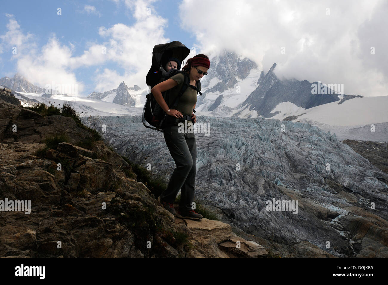 A lady hiker in the alps carrying her baby in a baby carrier on her ...