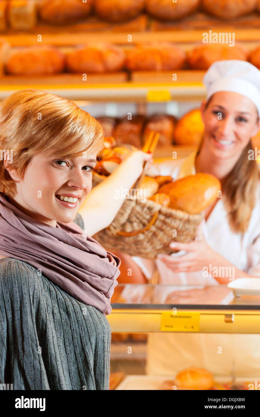 Female baker or saleswoman in her bakery with a female customer and ...