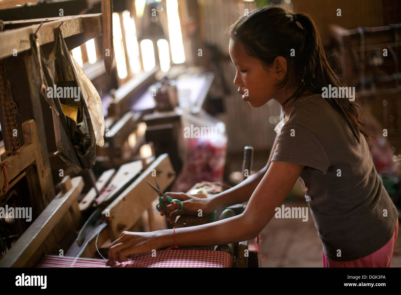 A young girl works in a village textile factory outside of Phnom Penh ...