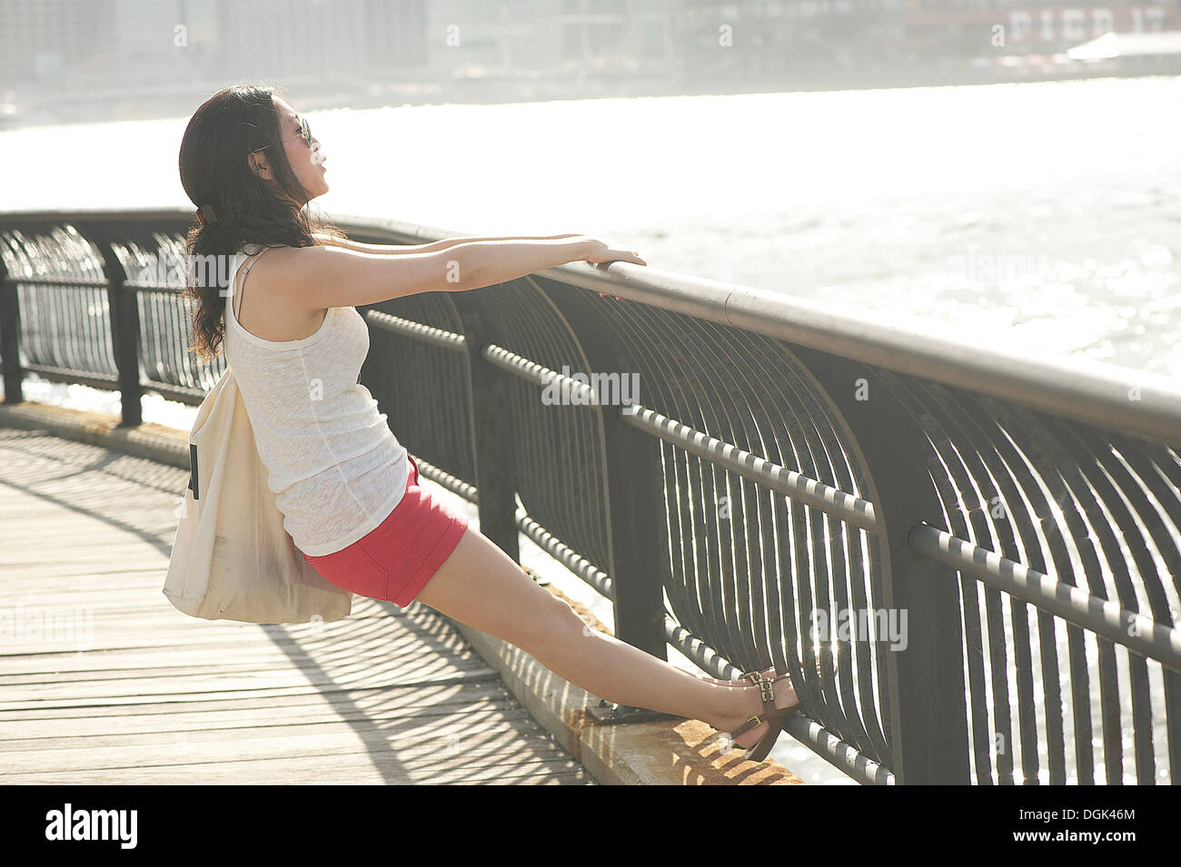 Young woman leaning back on railings looking at river Stock Photo - Alamy