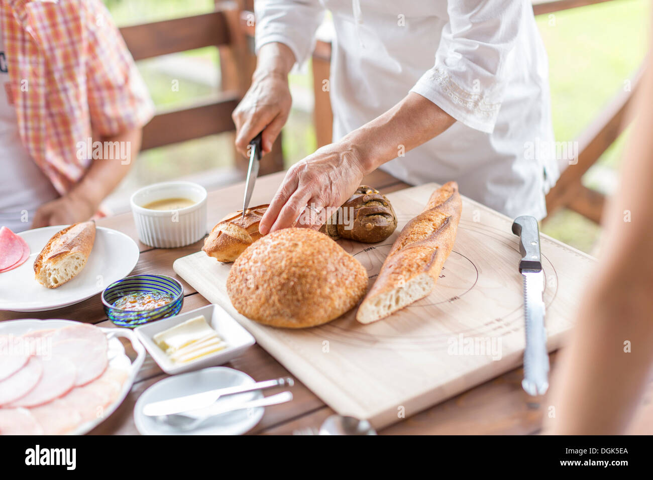 Woman cutting baguette Stock Photo - Alamy
