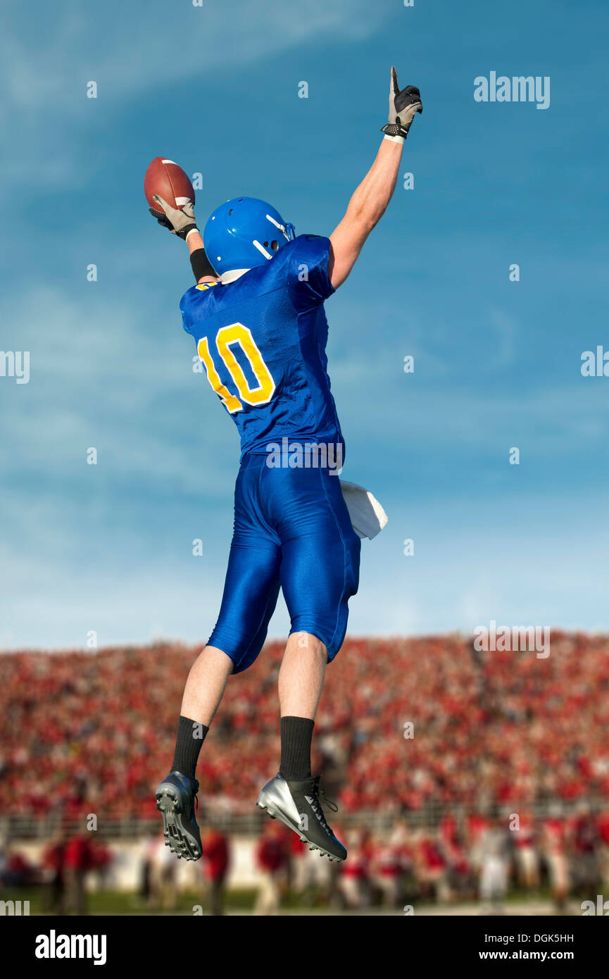 American footballer jumping with ball Stock Photo - Alamy