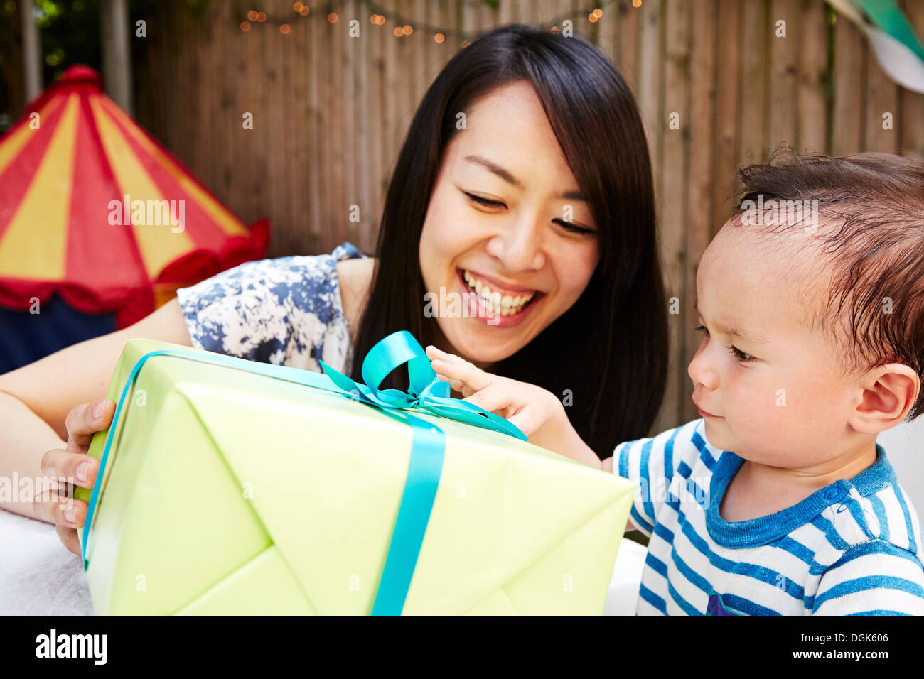 Mother giving baby boy a birthday present Stock Photo - Alamy