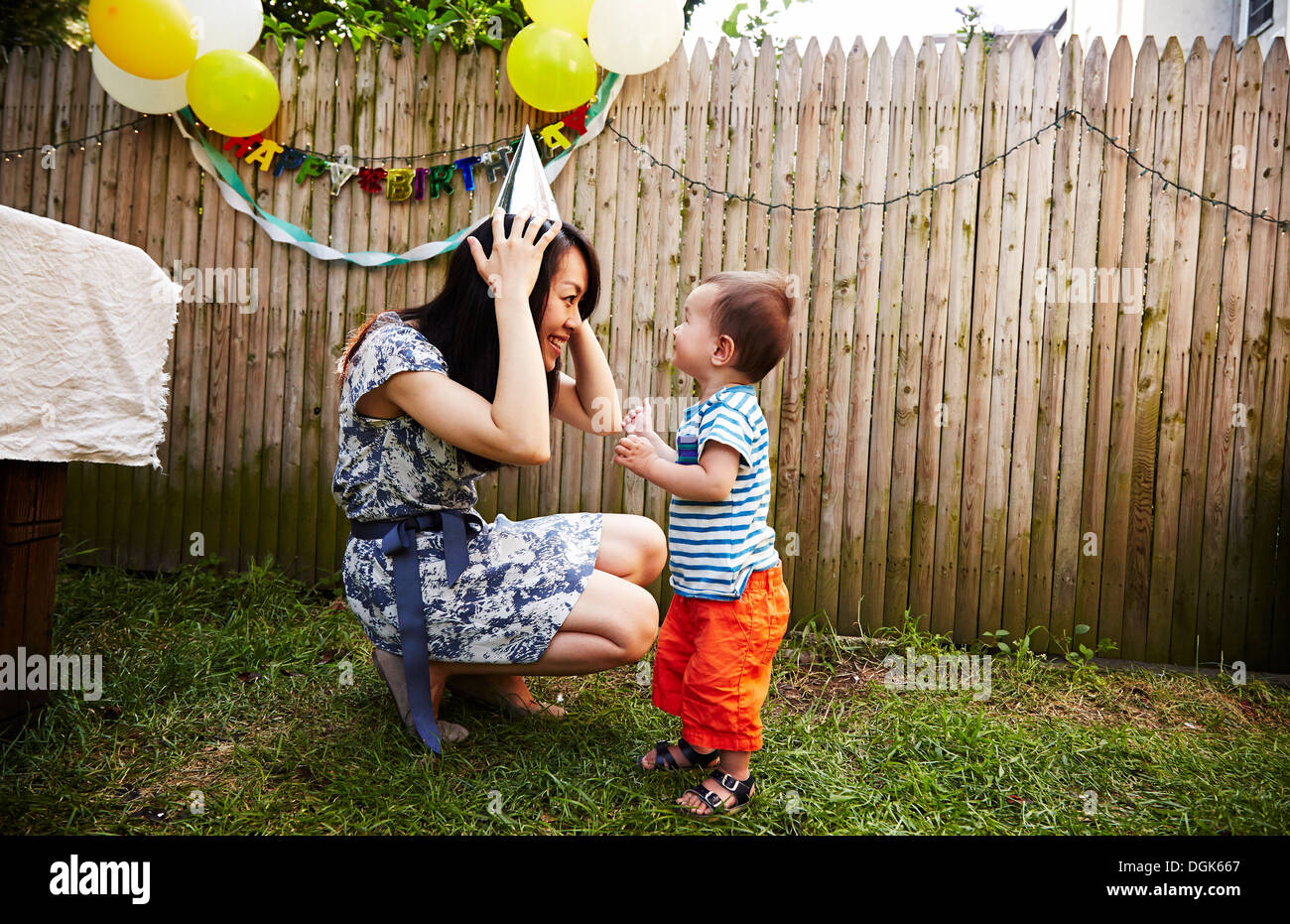 Mother crouching down putting on party hat Stock Photo - Alamy