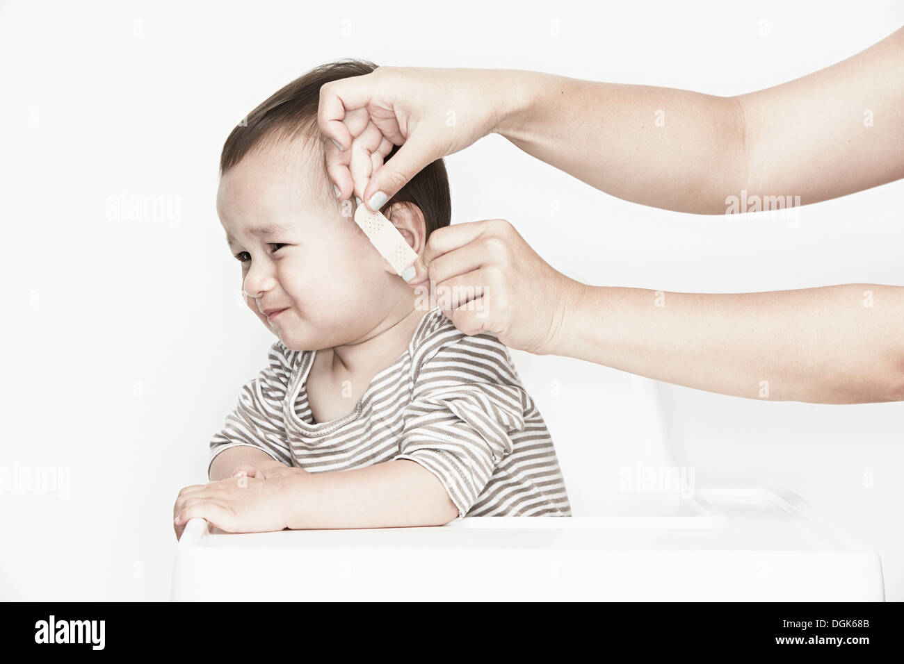 Hands applying plaster to baby's face Stock Photo - Alamy