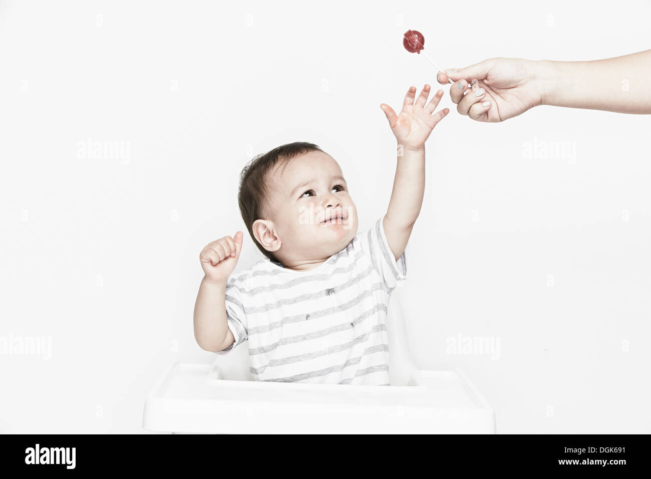 Baby boy reaching for lollipop Stock Photo - Alamy