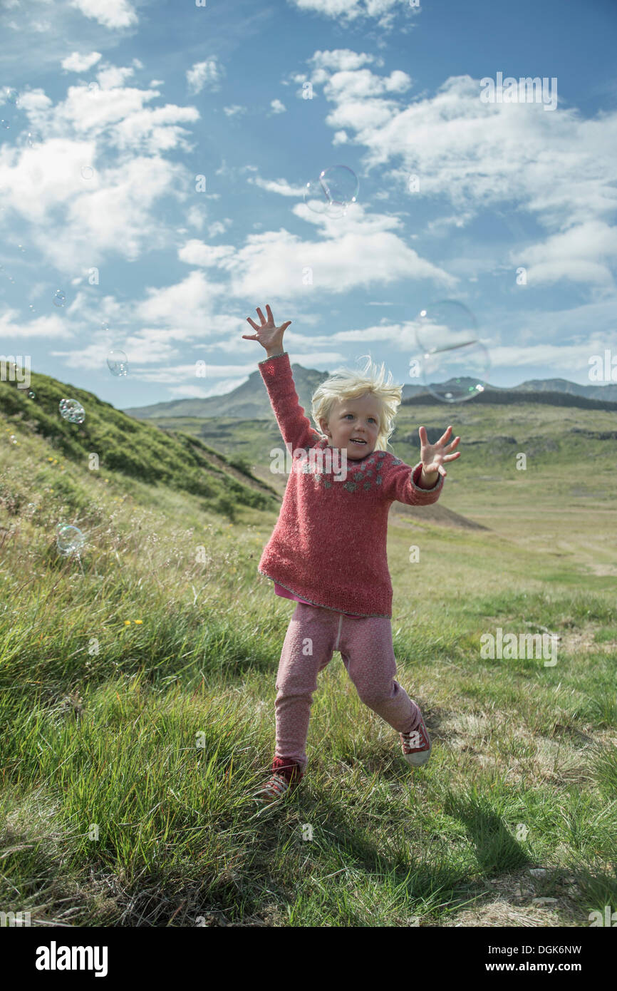 Young girl running to catch bubbles Stock Photo - Alamy