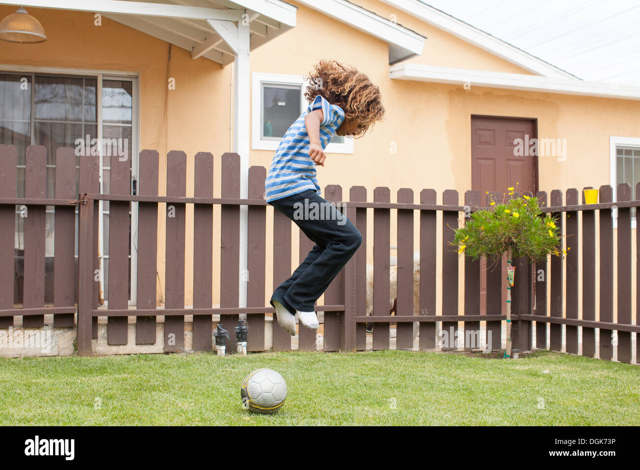 Boy jumping over football Stock Photo - Alamy