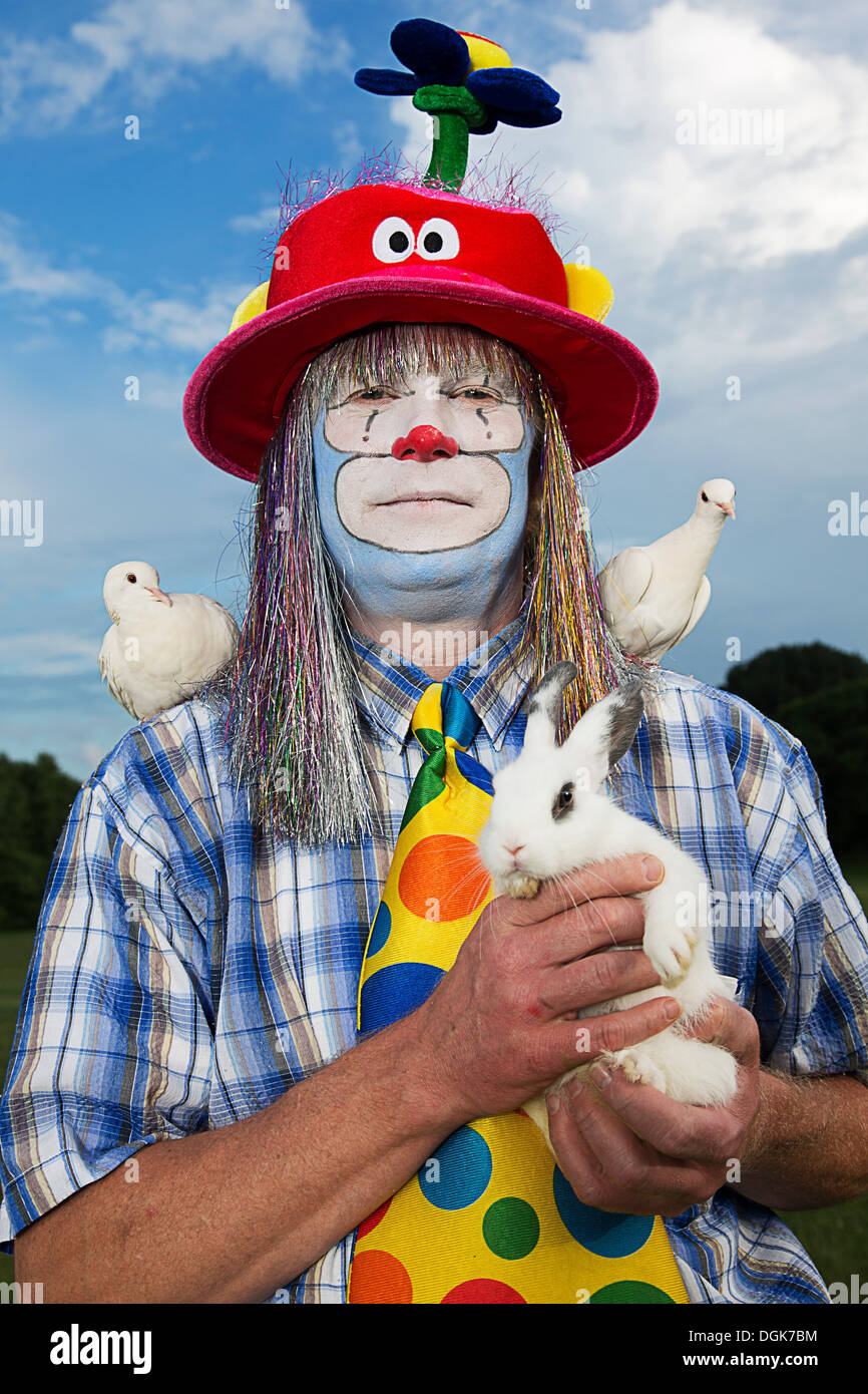 Portrait of clown holding a rabbit and with doves on shoulders Stock ...