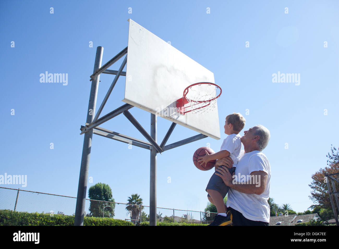 Man lifting grandson to basketball hoop Stock Photo - Alamy