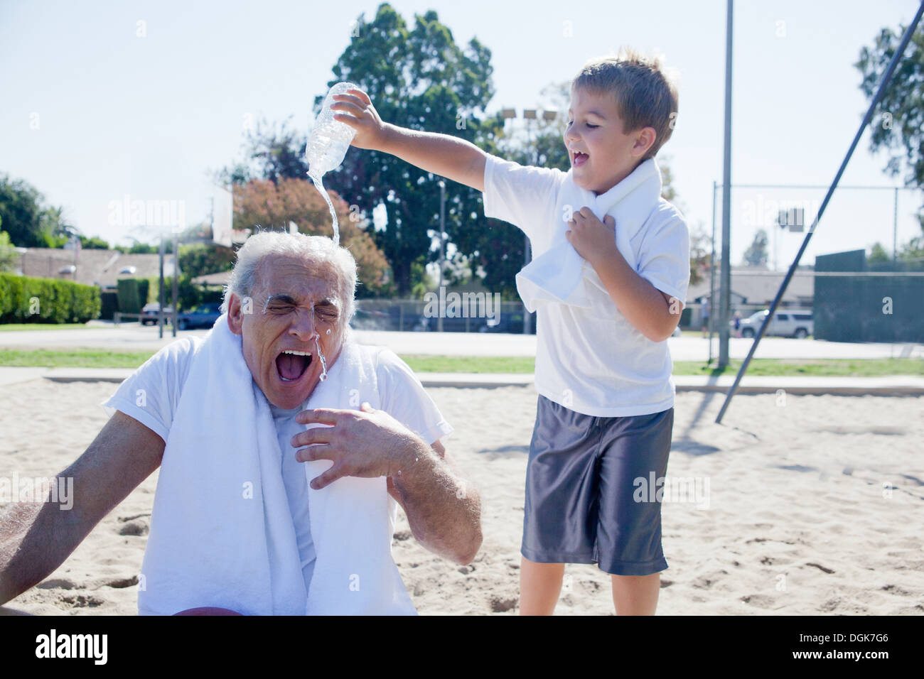 Boy pouring water on grandfather Stock Photo - Alamy