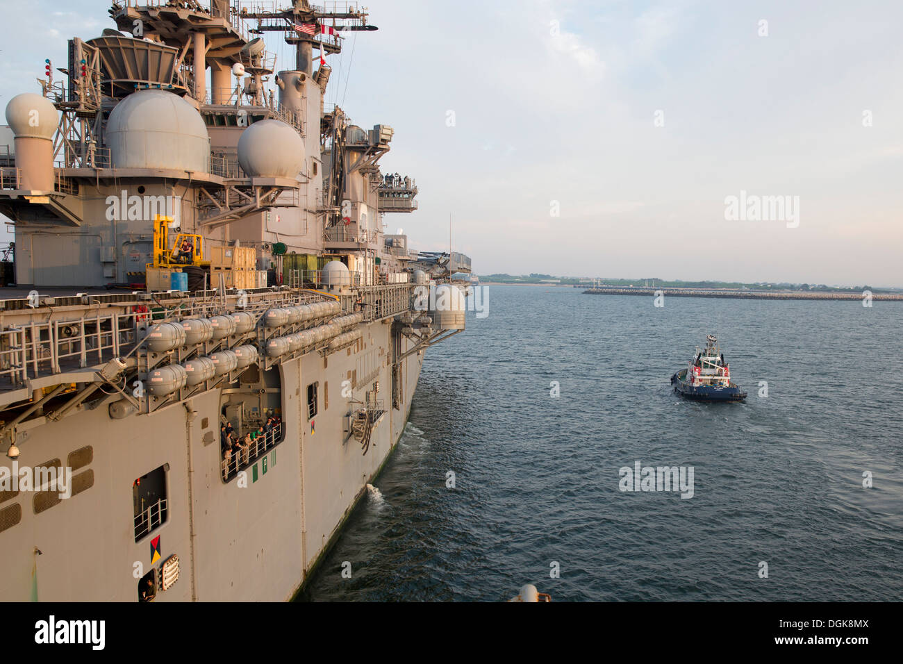 A tugboat approaches the amphibious assault ship USS Kearsarge (LHD 3 ...
