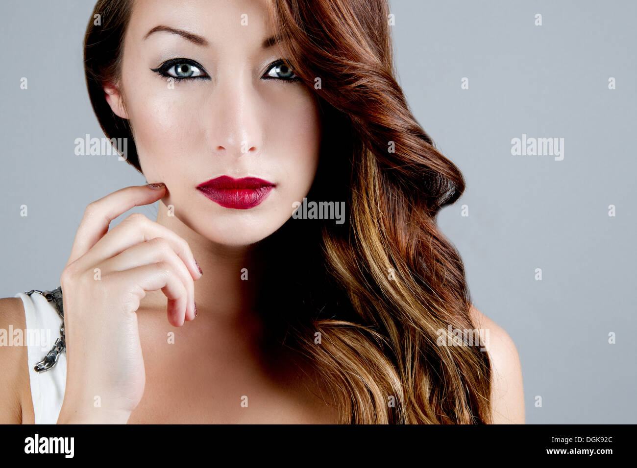 Studio portrait of brunette woman touching cheek Stock Photo - Alamy