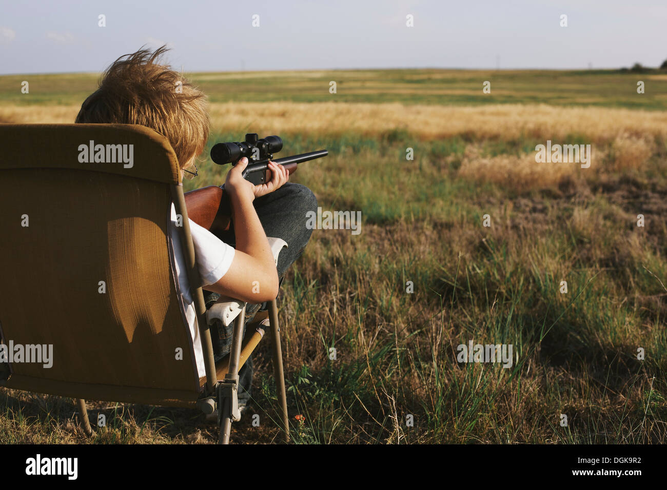 Boy on rural landscape pointing shotgun into distance Stock Photo - Alamy