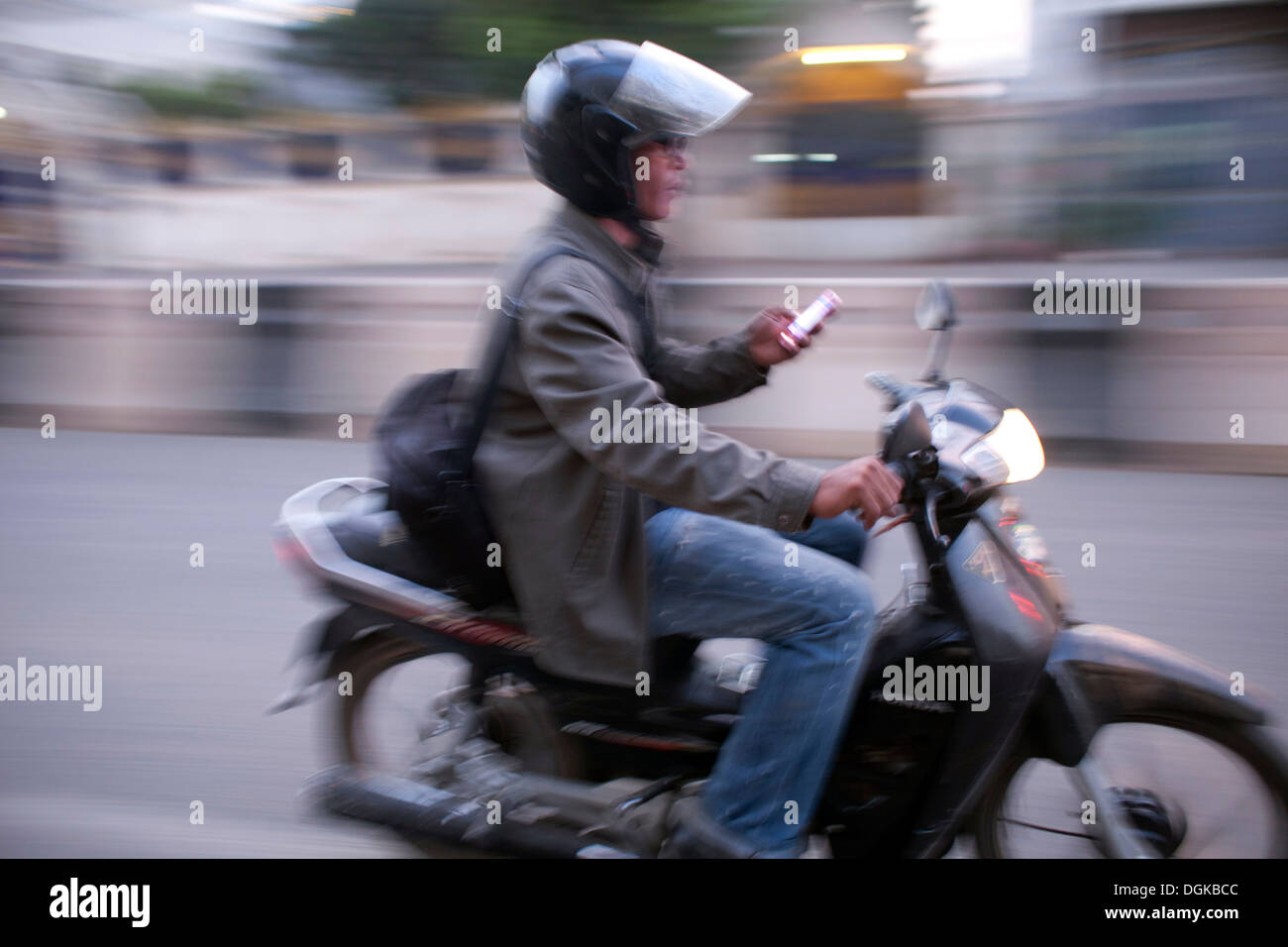 A motorcycle rider checks his smartphone in Phnom Penh, Cambodia ...