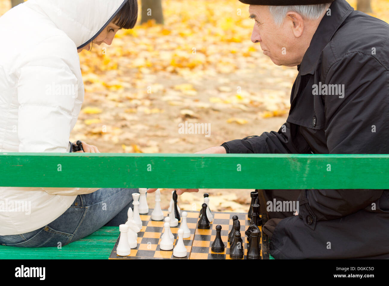 Senior gentleman playing chess sitting on a wooden park bench with a ...