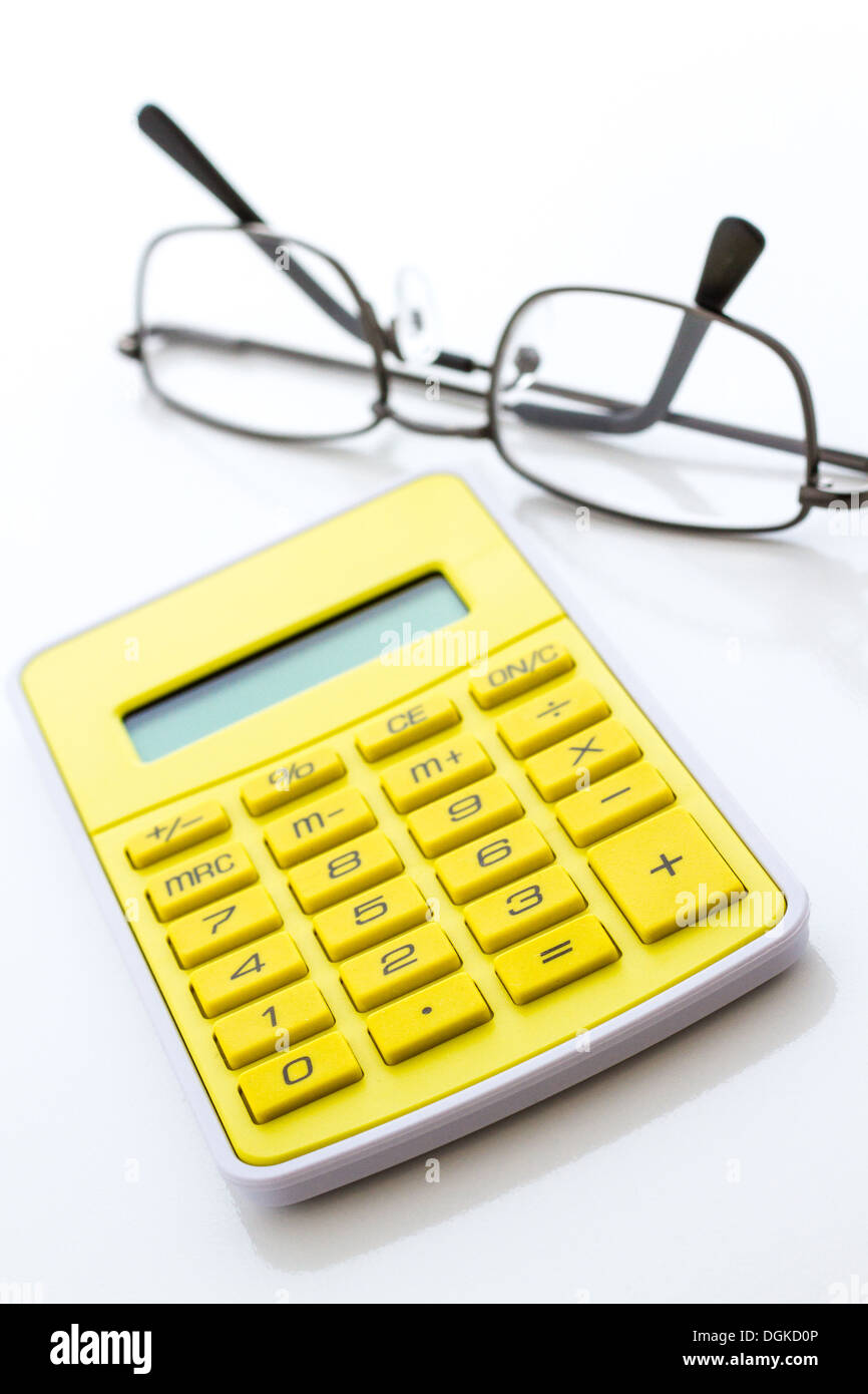 Simple yellow calculator with reading glasses on a white background ...