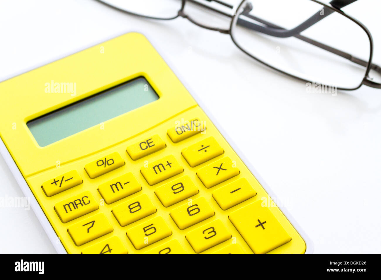 Simple yellow calculator with reading glasses on a white background ...