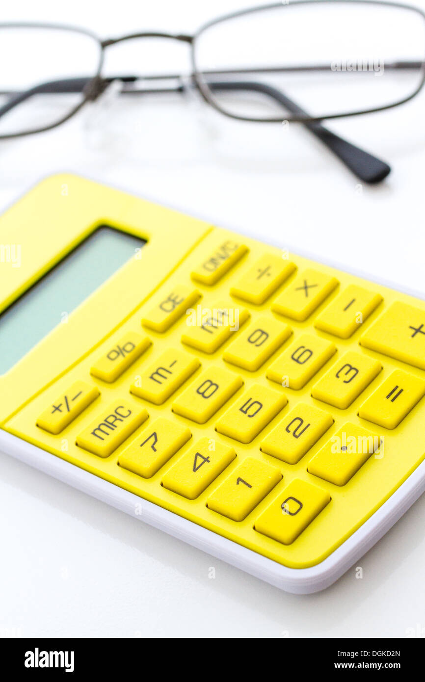 Simple yellow calculator with reading glasses on a white background ...