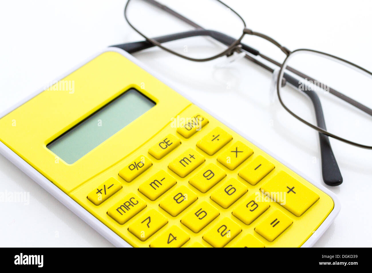 Simple yellow calculator with reading glasses on a white background ...