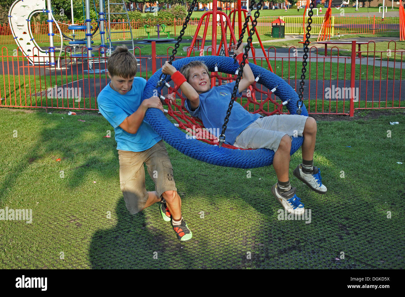 two young boys playing on a swing in the park Stock Photo - Alamy
