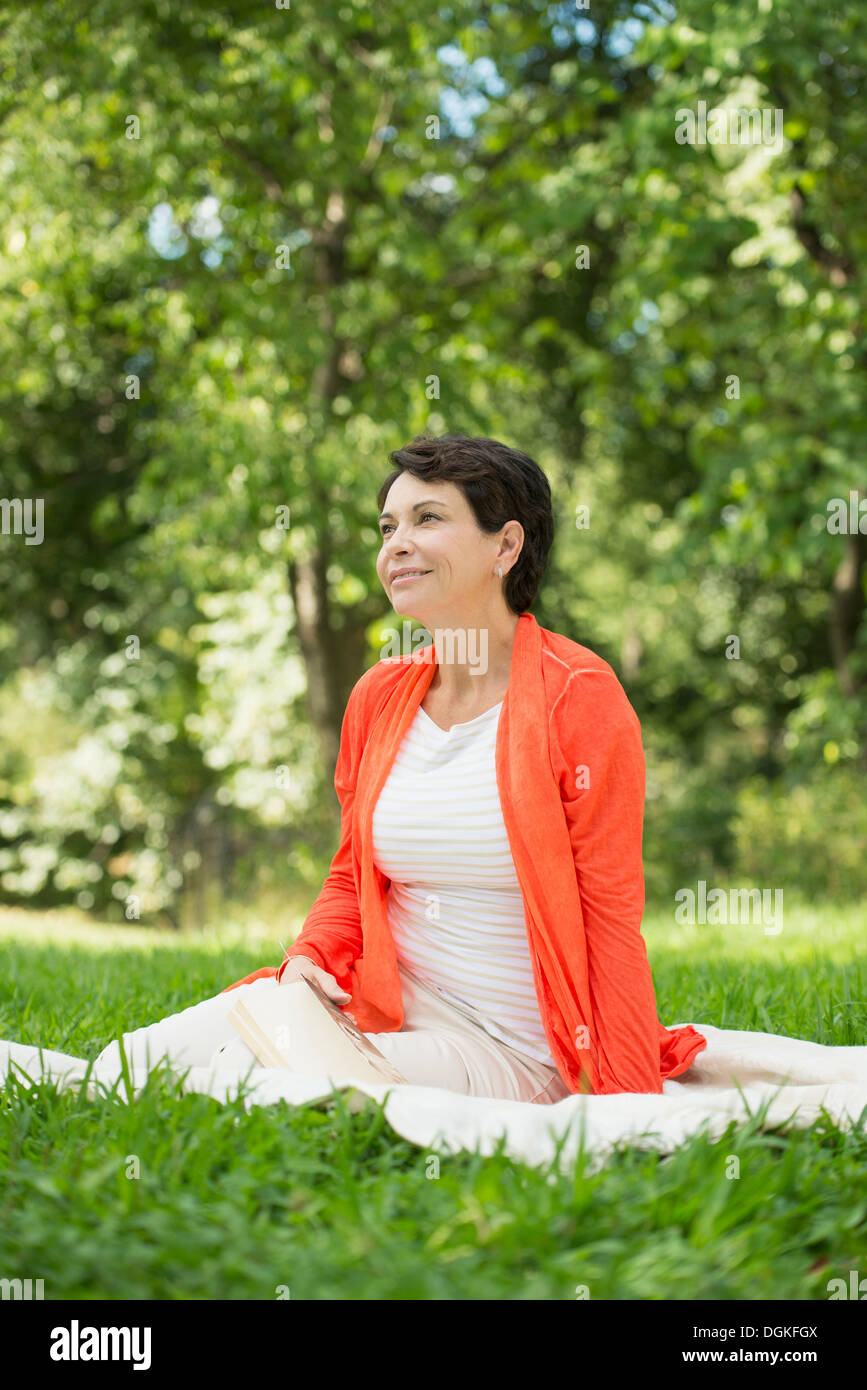 Mature woman sitting on grass in park Stock Photo - Alamy