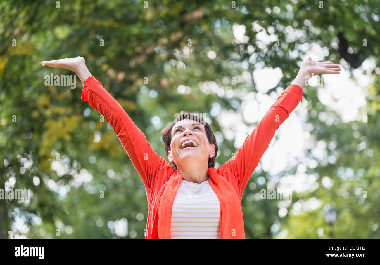 Happy mature woman raising hands in park Stock Photo - Alamy