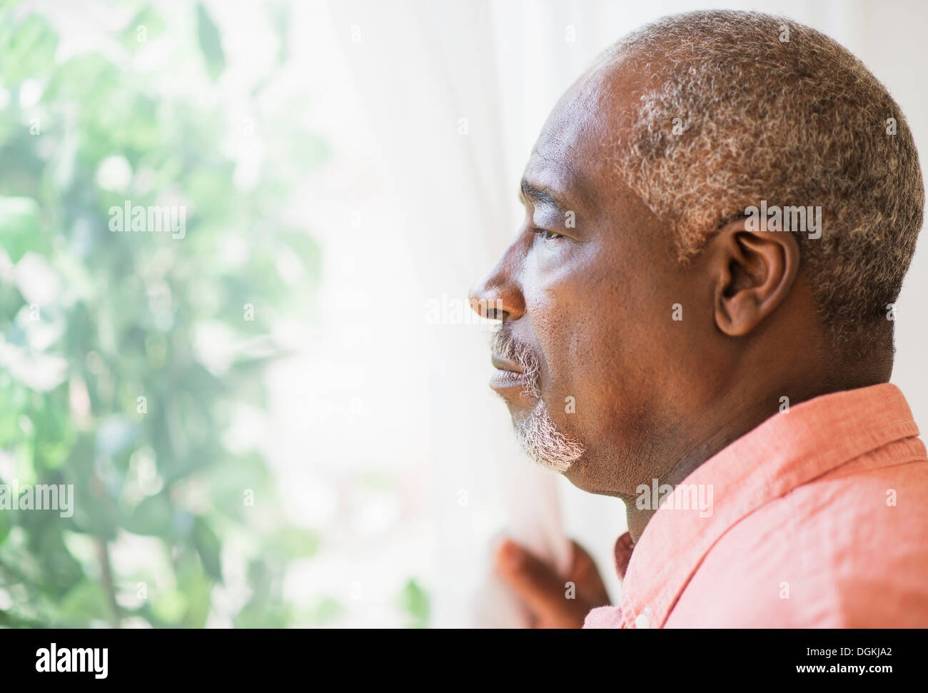 Portrait of man looking through window Stock Photo - Alamy