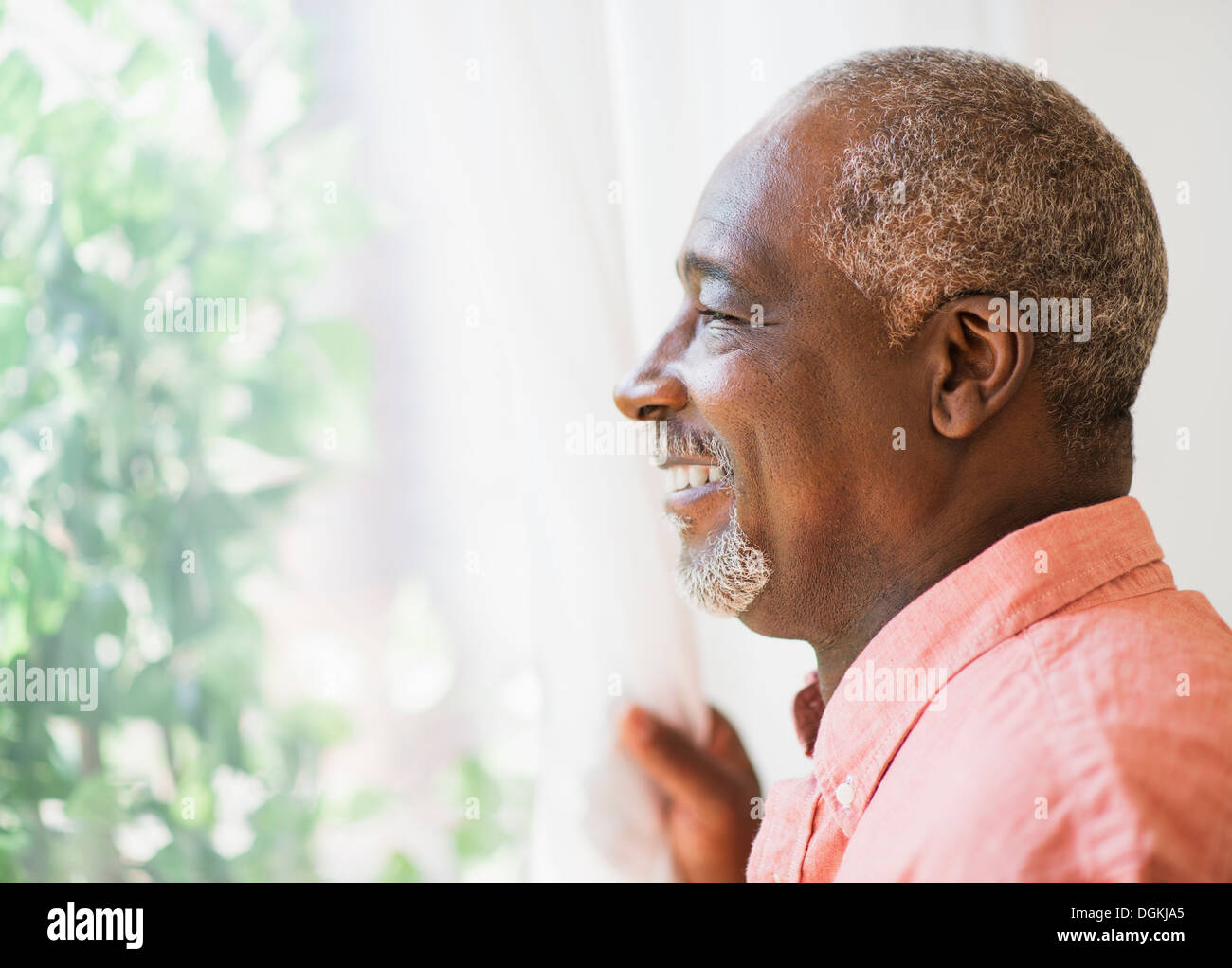 Portrait of smiling man looking through window Stock Photo - Alamy