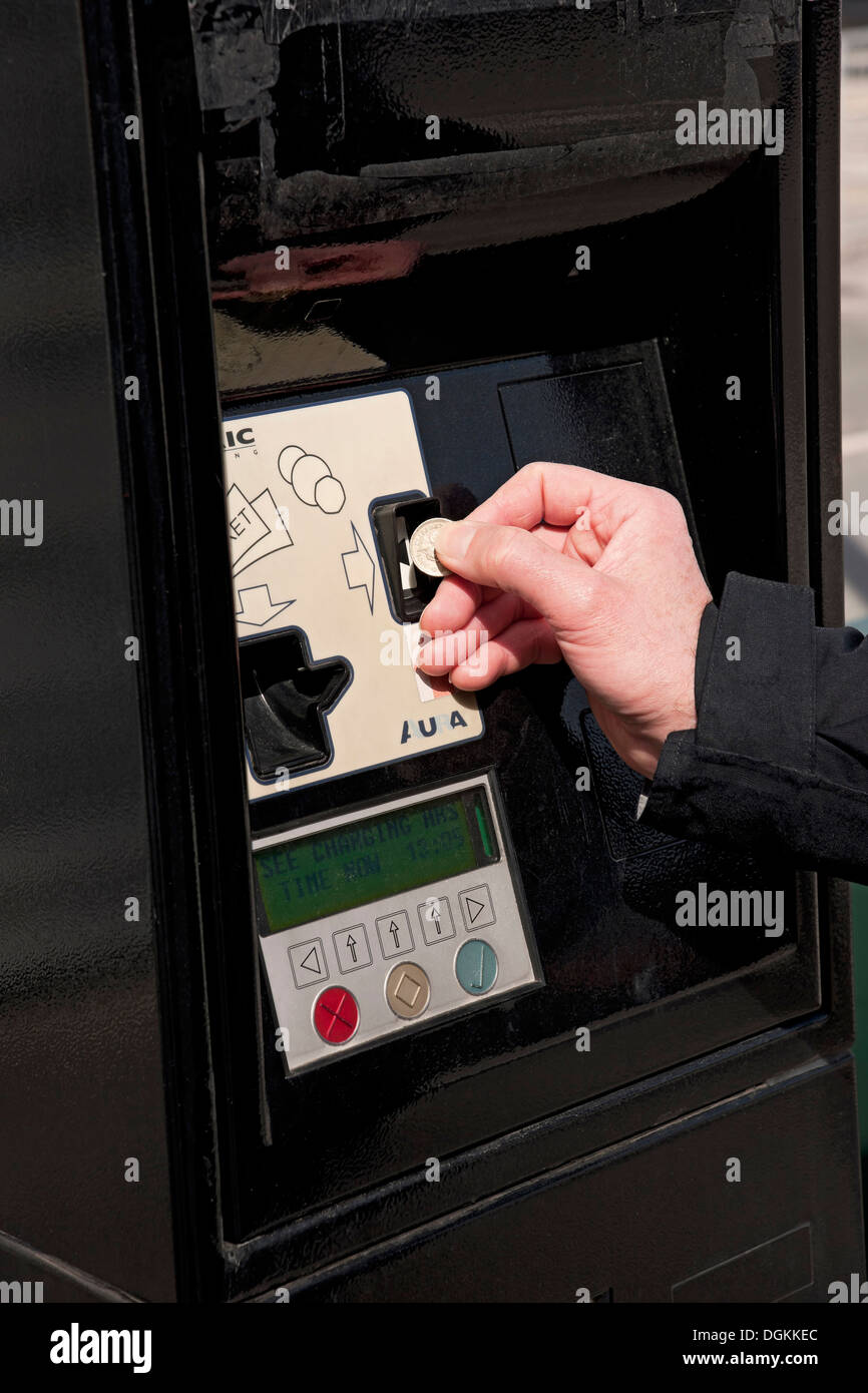 A man putting a coin into a car park meter Stock Photo - Alamy