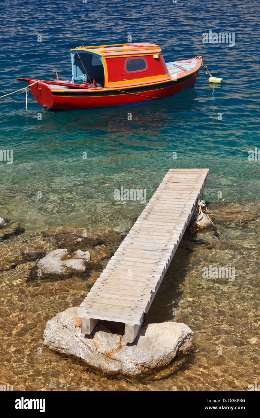 A single red boat and wooden jetty on the island of Symi Stock Photo ...