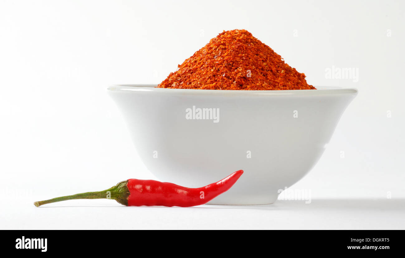 Chili powder in a small bowl and chili pepper Stock Photo - Alamy