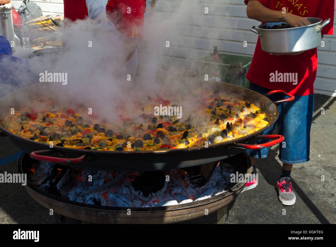 A large pan of paella cooking on a wood fire at a seafood festival in ...