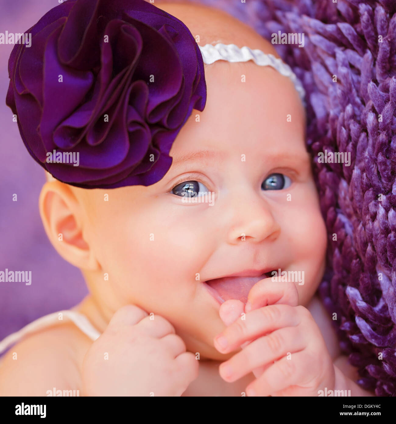 Closeup portrait of happy newborn girl wearing fashionable purple head ...