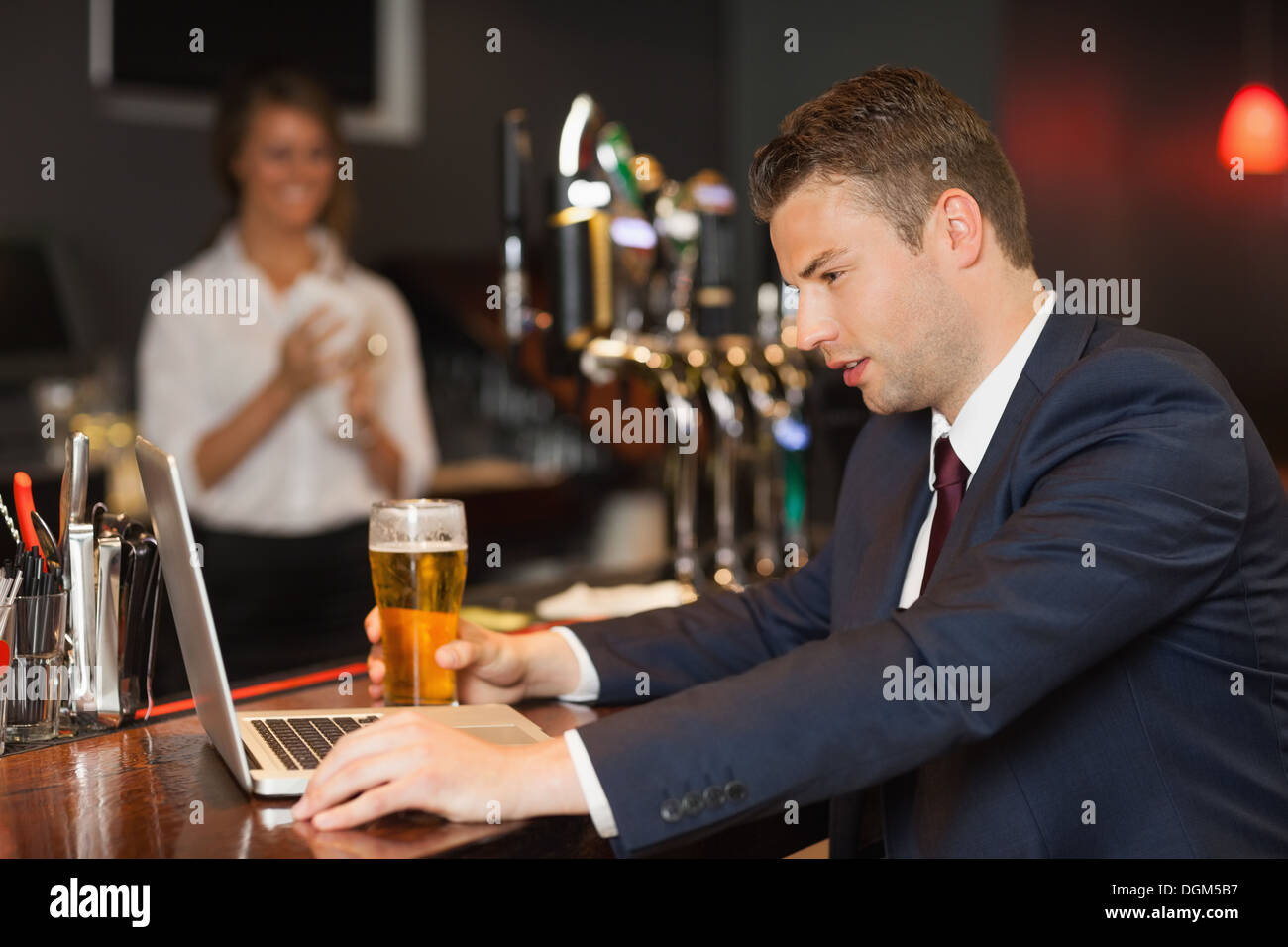 Businessman having a beer while working on his laptop Stock Photo - Alamy