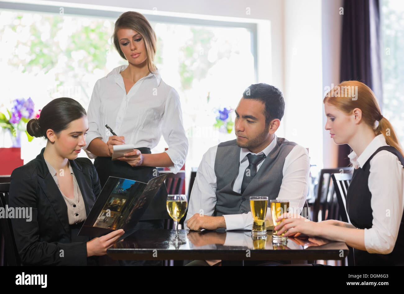 Three business people ordering dinner from waitress Stock Photo - Alamy
