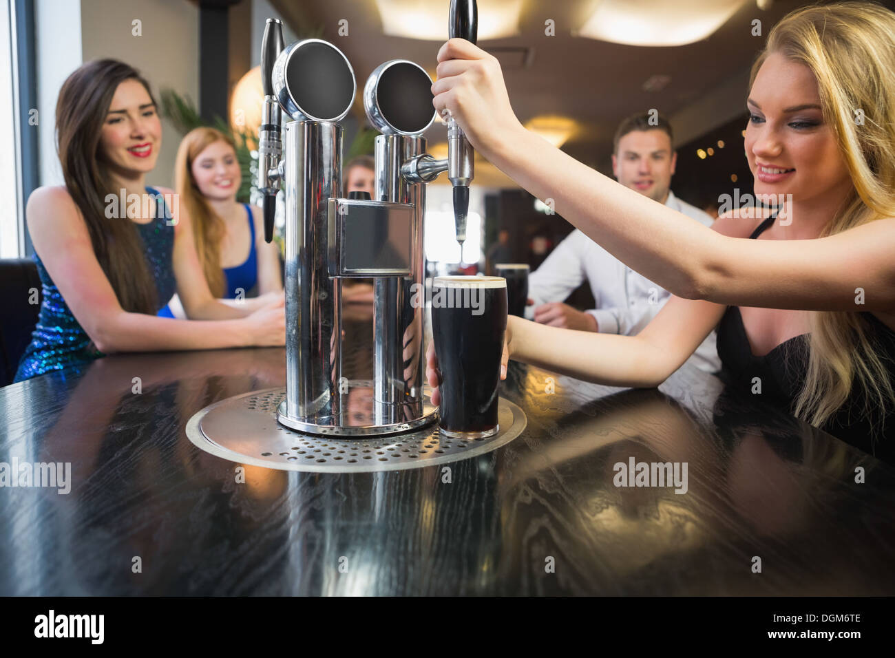 Blonde woman pulling a pint of stout Stock Photo - Alamy