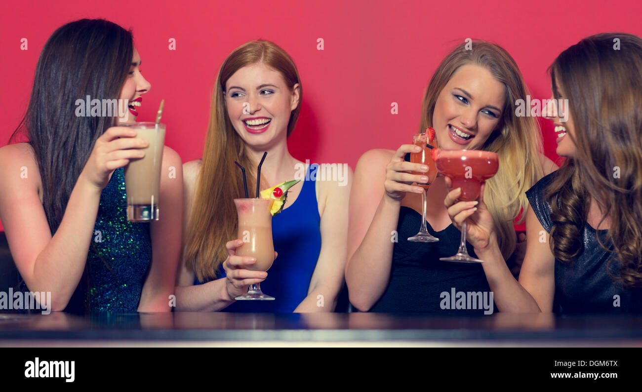 Four friends having a party holding cocktails Stock Photo - Alamy