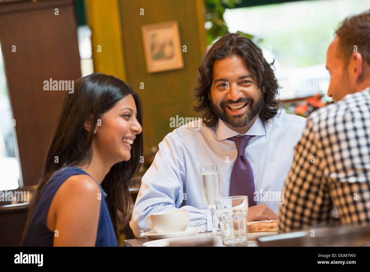 Business people. Three people seated around a table in a bar or cafe ...