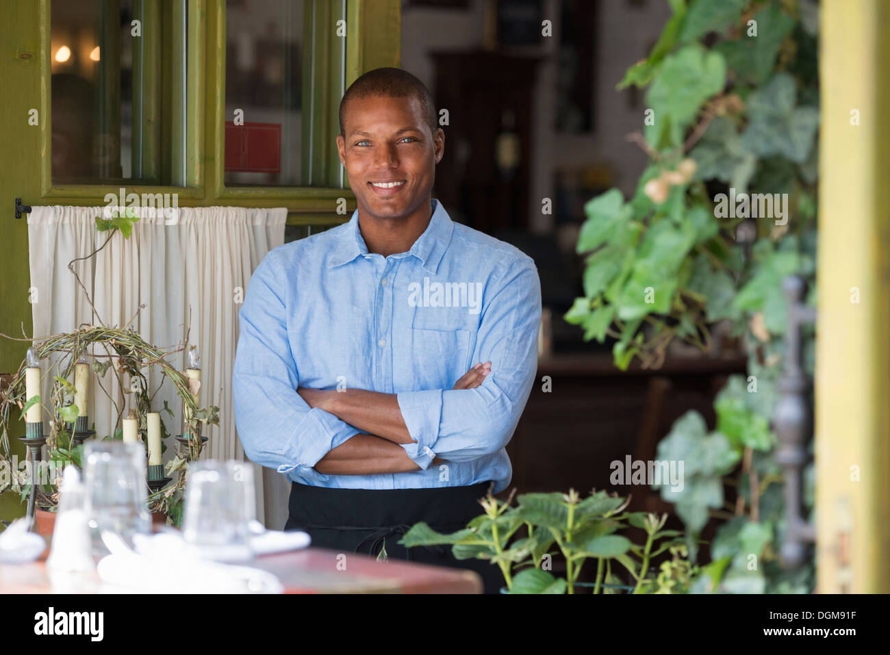 A man standing by the open window of a cafe or bistro, looking out with ...