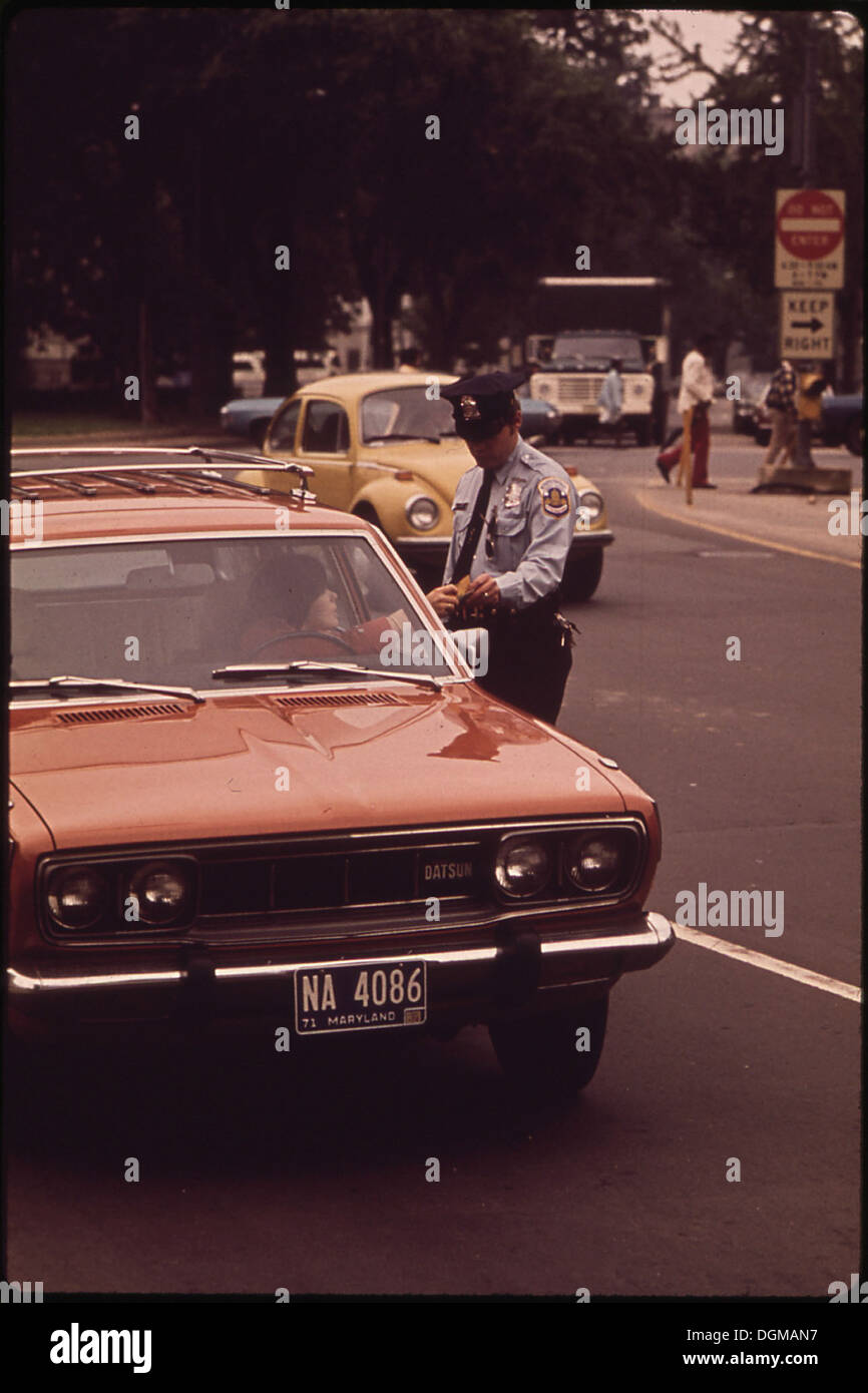 This photograph captures a police officer issuing a ticket to a driver ...