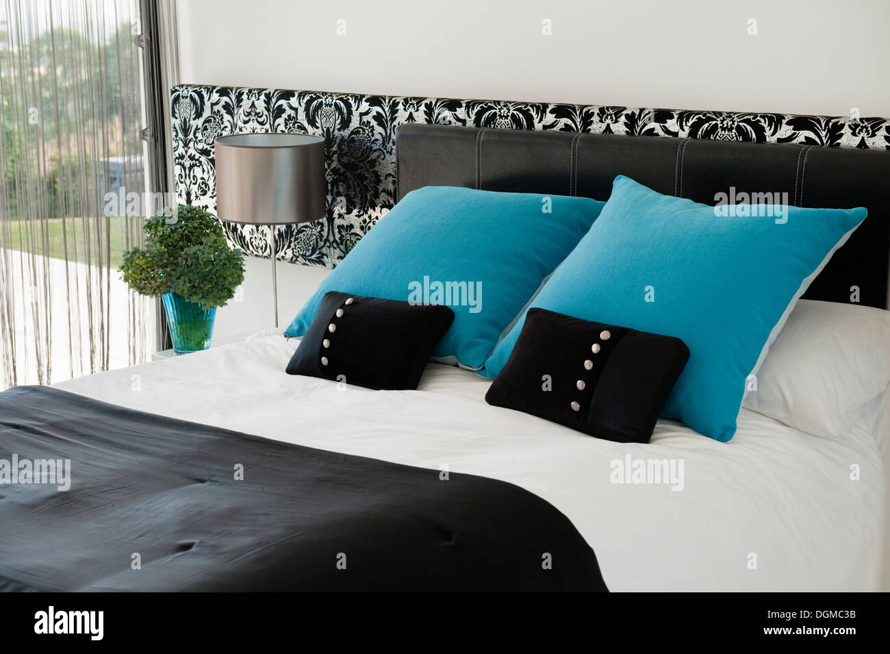 Bright blue cushions on bed with flock effect metallic headboard Stock ...