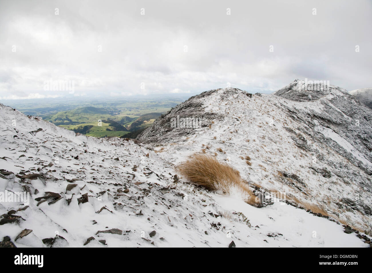 Snow-covered mountain crest and a green valley in the distance, near ...
