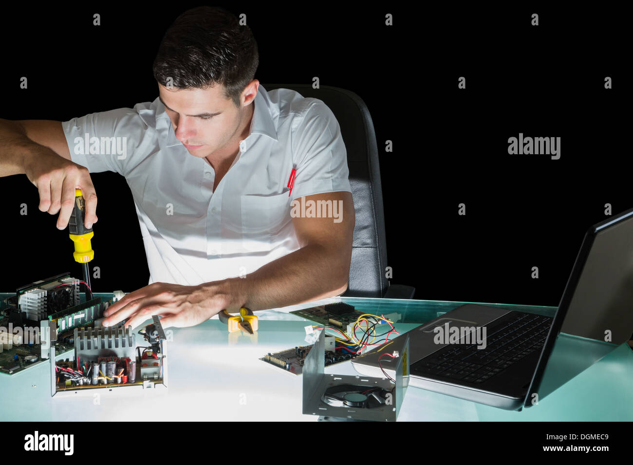 Handsome stern computer engineer working by night with screw driver ...