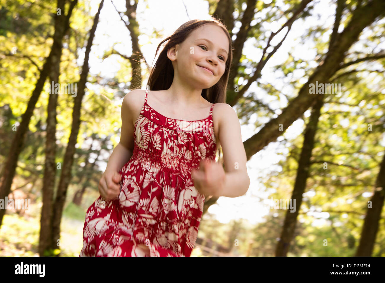 A young girl running along through trees on a farm Stock Photo - Alamy