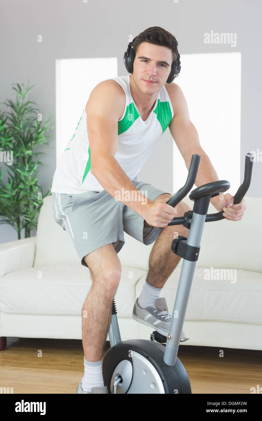 Content handsome man training on exercise bike listening to music Stock ...