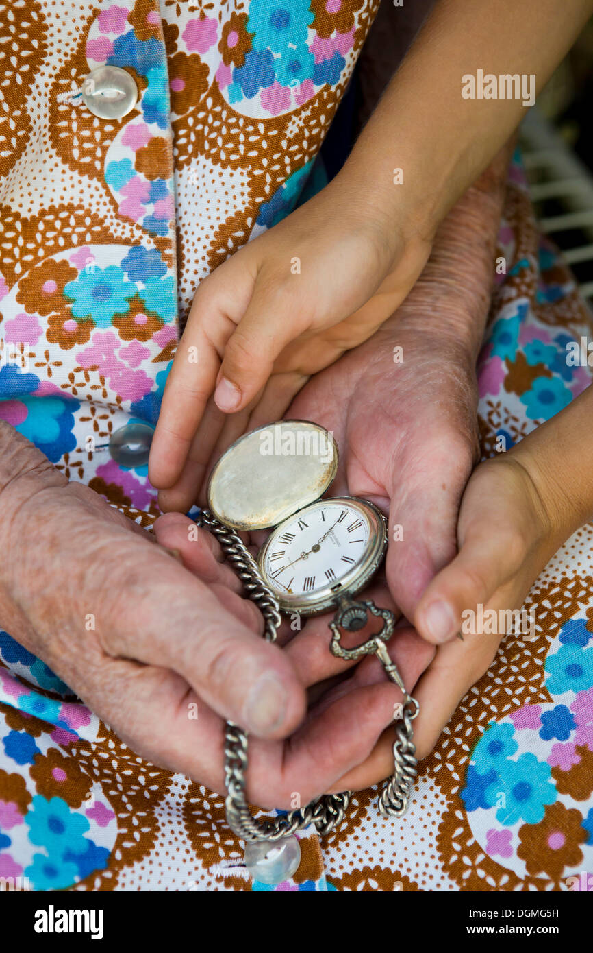 Elderly woman and a child holding an old pocket watch in their hands ...