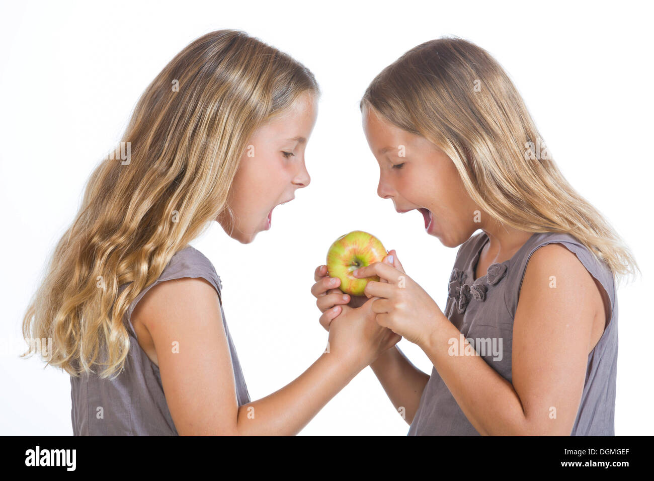 Twin girls, 9, biting into an apple Stock Photo - Alamy