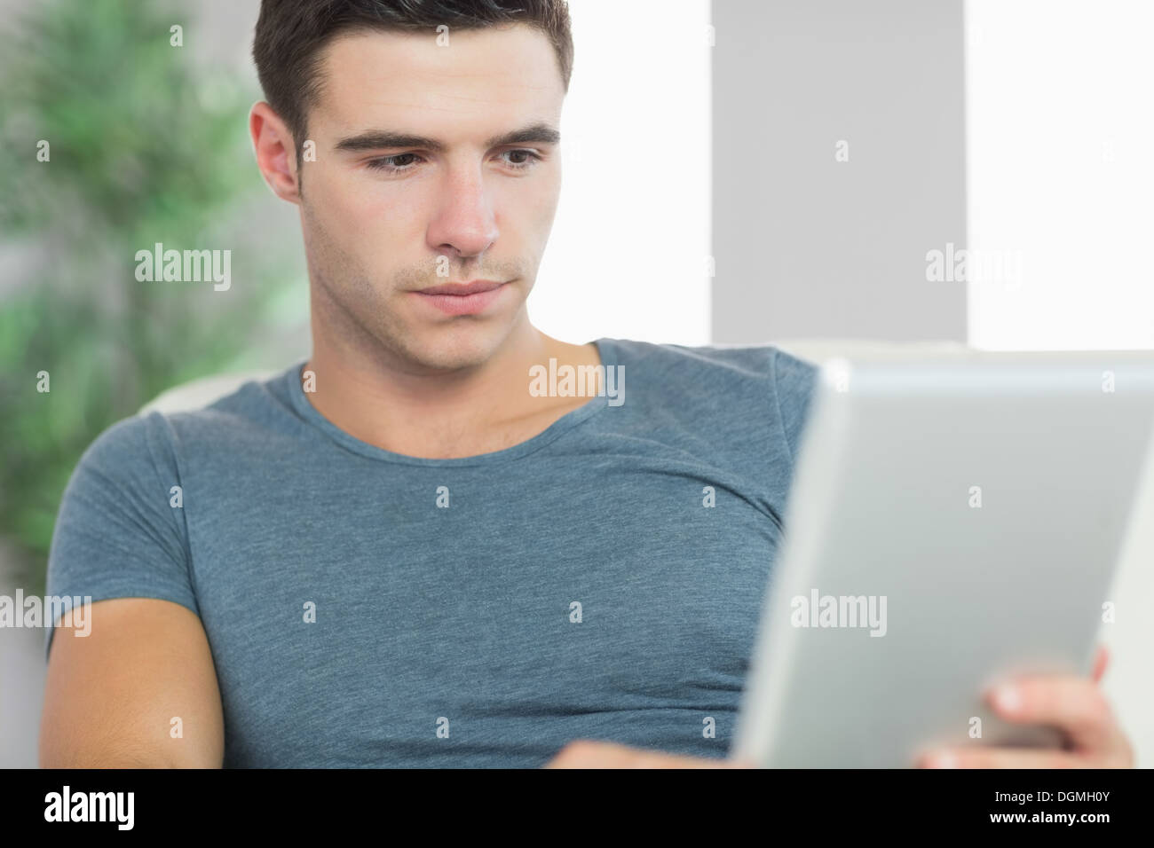 Serious handsome man relaxing on couch using tablet Stock Photo - Alamy Serious handsome man relaxing on couch using tablet Stock Photo - Alamy