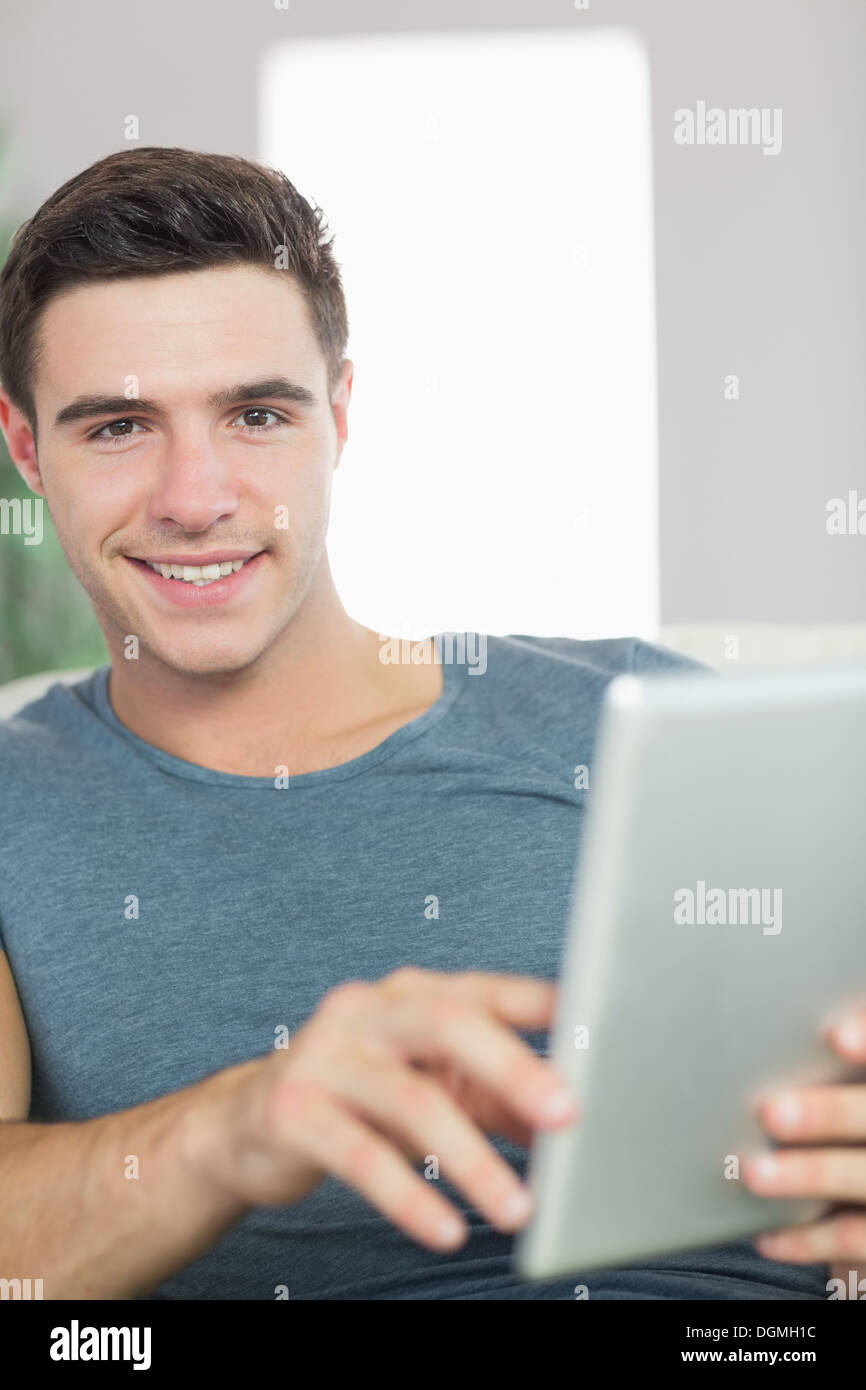 Laughing handsome man relaxing on couch using tablet Stock Photo - Alamy